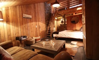 Um quarto aconchegante, com decoração em madeira, com uma cama, uma mesa de centro e um sofá.