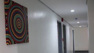 Um corredor com uma obra de arte colorida na parede, um alarme de incêndio e um chão limpo e brilhante.