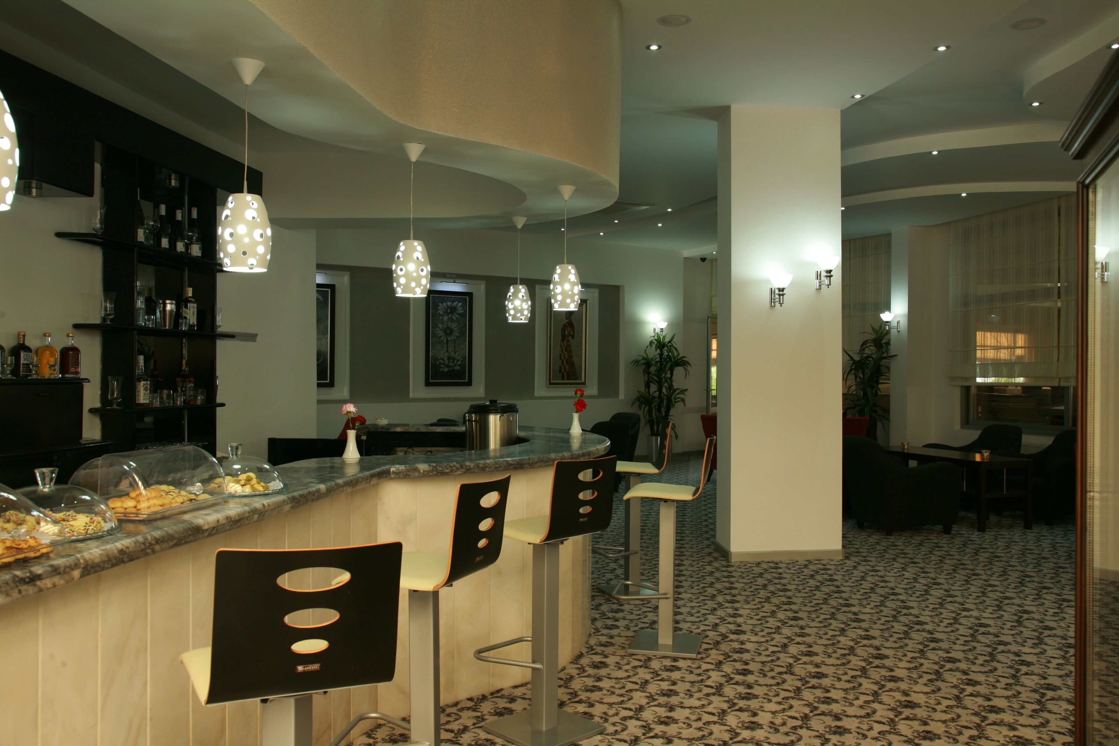 Cozinha moderna com bancada de mármore, banquetas e iluminação pendente.