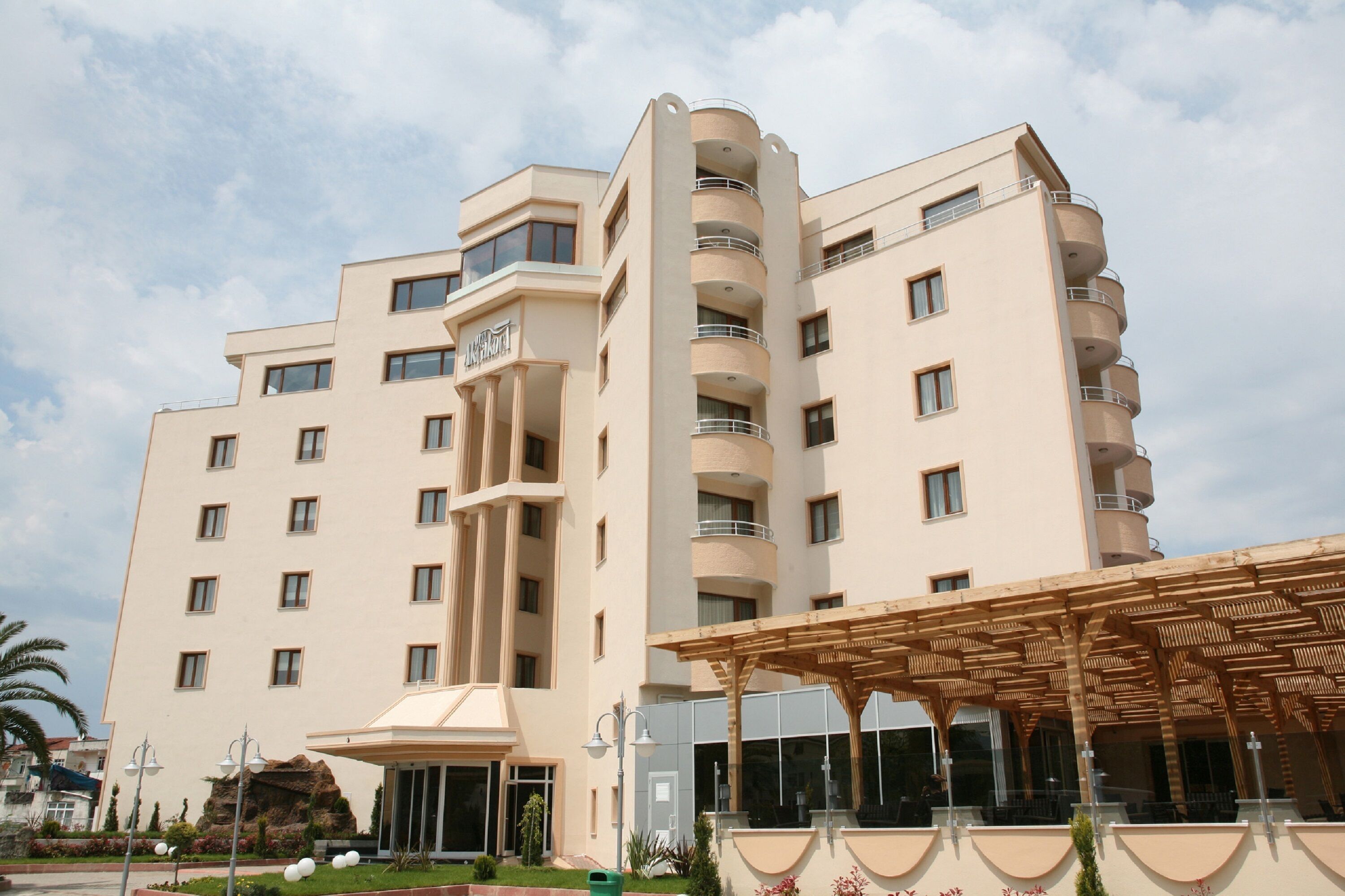 Um hotel com vários andares e design arquitetônico moderno, com varandas em cada pavimento e uma entrada central com área coberta.
