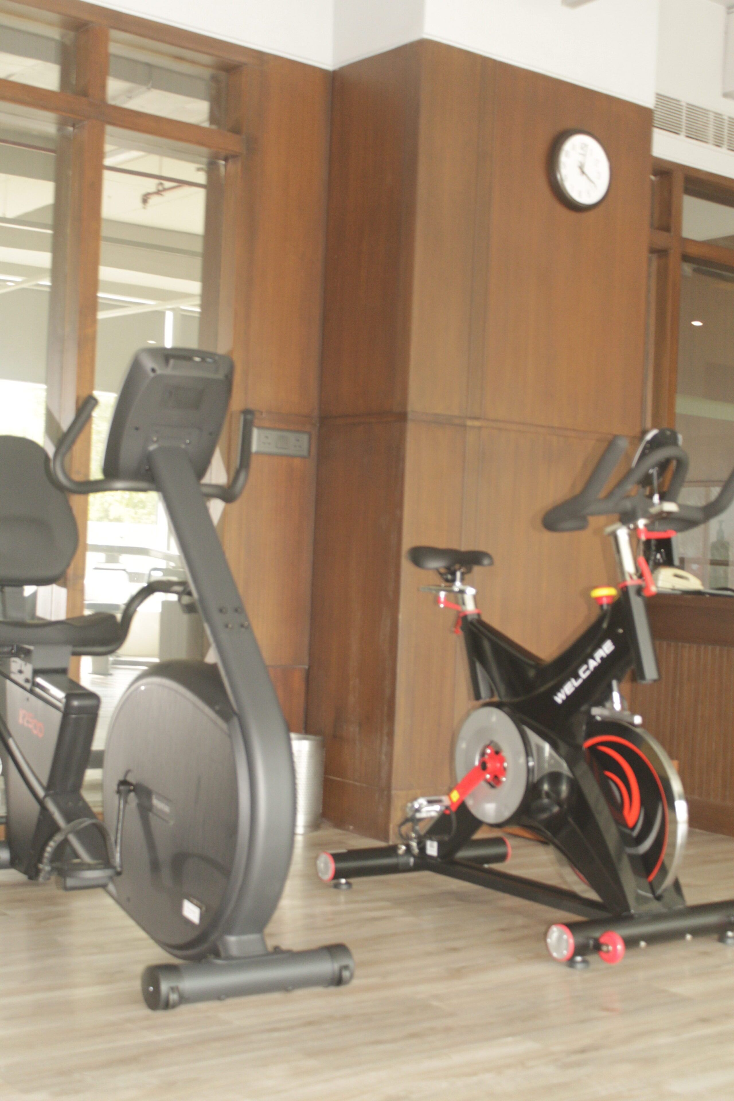Uma academia com equipamentos de exercício, incluindo uma bicicleta ergométrica e um elíptico.