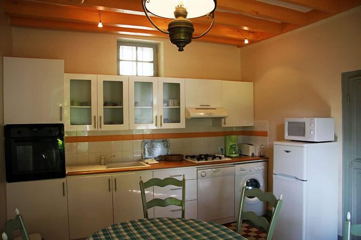 Uma cozinha compacta com armários brancos, micro-ondas, fogão e máquina de lavar louça.