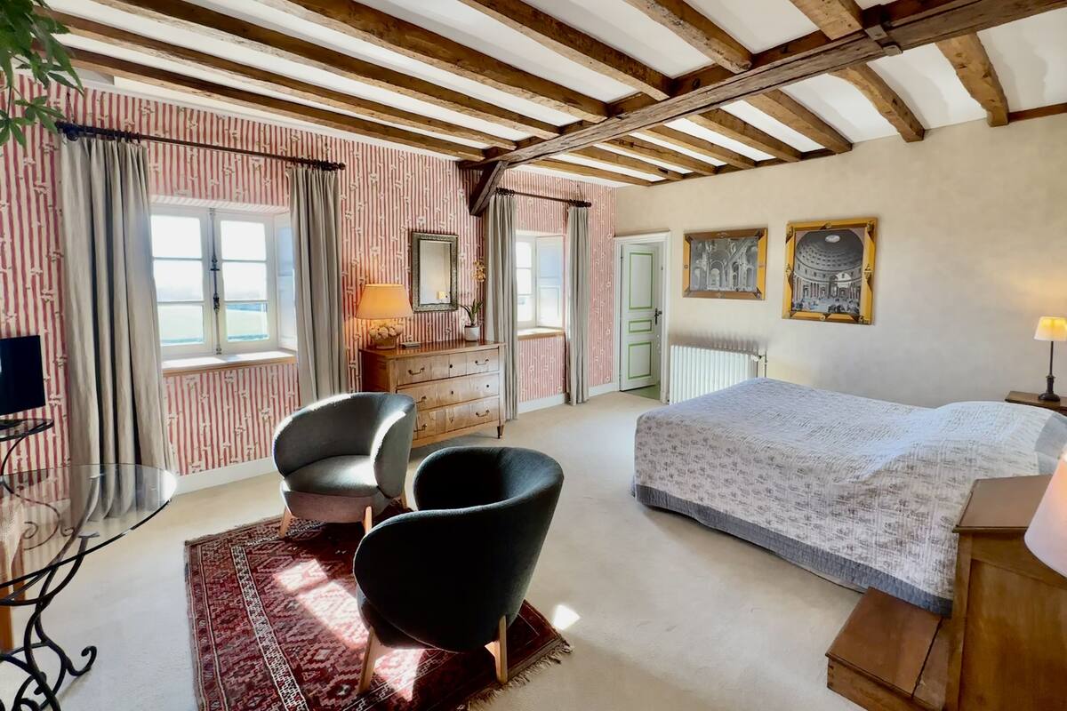 Quarto com cama, duas cadeiras, penteadeira, espelho, janela e radiador.