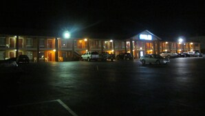 Um motel com várias vagas de estacionamento e entrada bem iluminada.