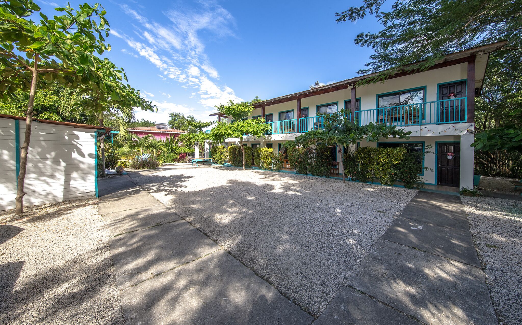 Pátio com um edifício com varandas e um caminho de cascalho.