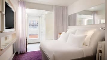 Quarto de hotel com cama, televisão, banheiro e vista para o exterior.