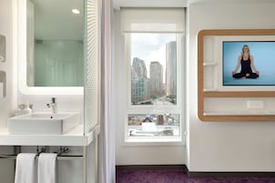 Casa de banho moderna com um espelho grande, lavatório e janela com vista para a cidade.