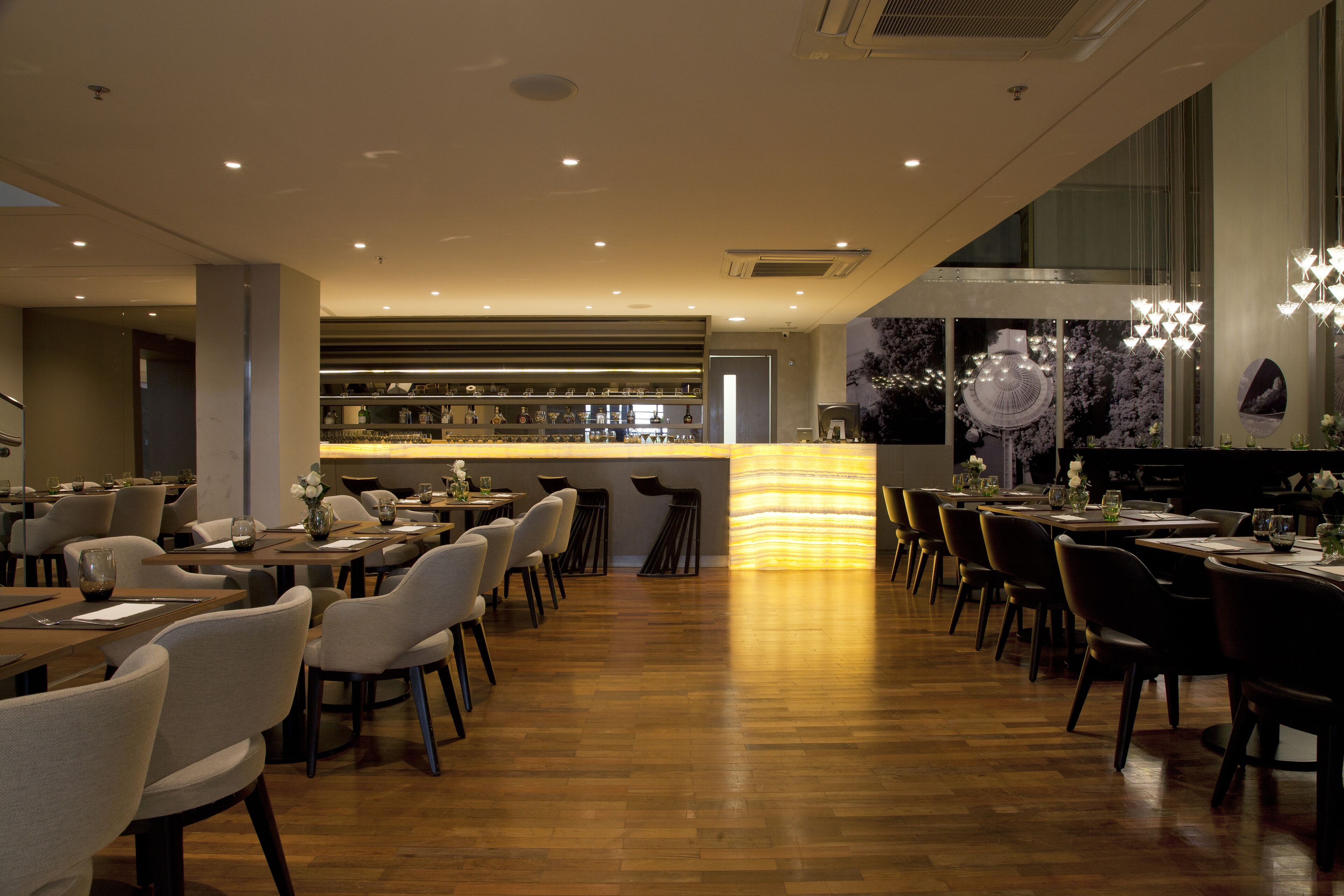 Um restaurante amplo, com piso de madeira, diversas mesas e cadeiras.