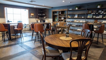 Restaurante com mesa redonda central, vários bancos altos e área de estar com cadeiras.