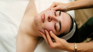 Uma pessoa deitada com as mãos no rosto, possivelmente recebendo um tratamento facial.