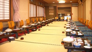 Um quarto japonês tradicional com esteiras de tatame, mesas baixas e almofadas.