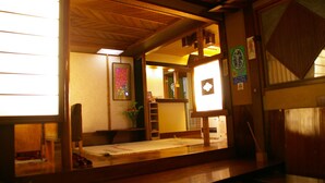 Um interior japonês tradicional com tatames, uma mesa de madeira baixa e portas deslizantes.