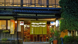 Um edifício japonês tradicional com fachada de madeira e toldo verde.