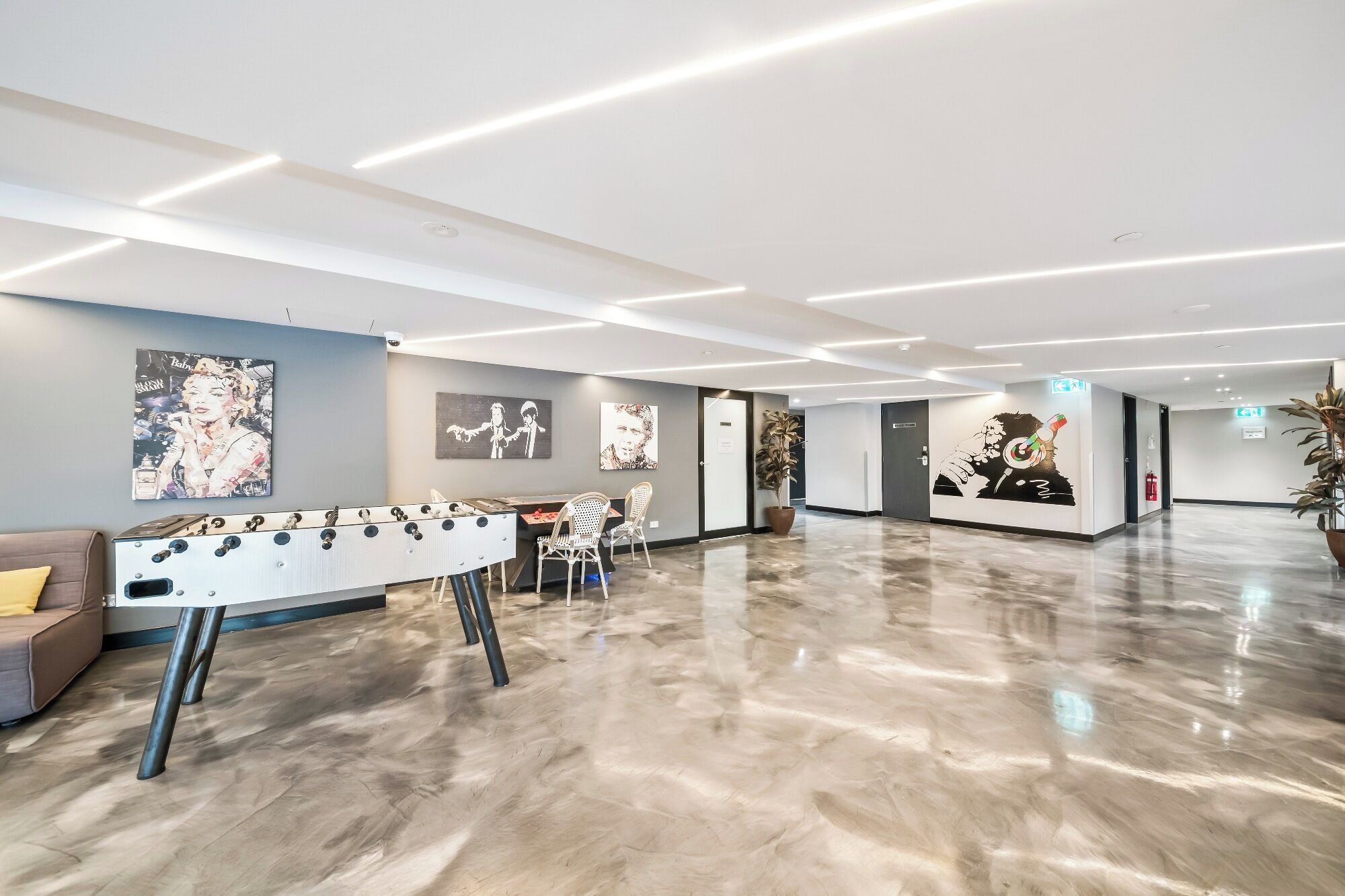 Um lobby moderno com mesa de pebolim, obras de arte nas paredes e piso limpo e lustroso.