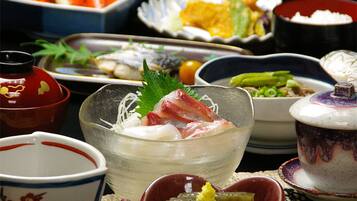 Diversos pratos japoneses, incluindo sashimi e sushi, servidos em louças de cerâmica tradicionais.