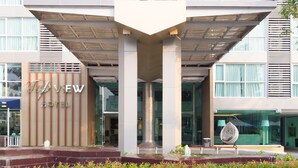 Entrada de hotel moderna com um destaque para a placa 'Hotel View', uma coluna central e uma área de estar com cadeira suspensa.