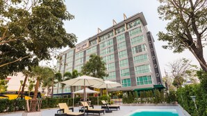Um hotel com piscina no terraço, espreguiçadeiras e guarda-sóis.