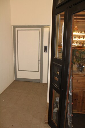 Um corredor com uma porta fechada e um espaço de bar com prateleiras cheias de garrafas.