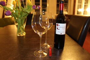 Uma garrafa de vinho e dois copos de vinho sobre uma mesa de madeira.