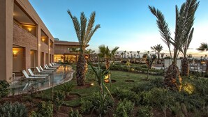Um resort com área de piscina, espreguiçadeiras e palmeiras.