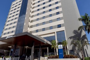 Um hotel moderno com fachada imponente, vários andares e entrada destacada com marquise.