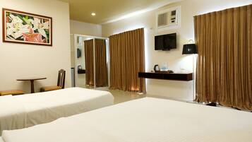 Quarto de hotel com duas camas, televisão, cafeteira e um quadro na parede.