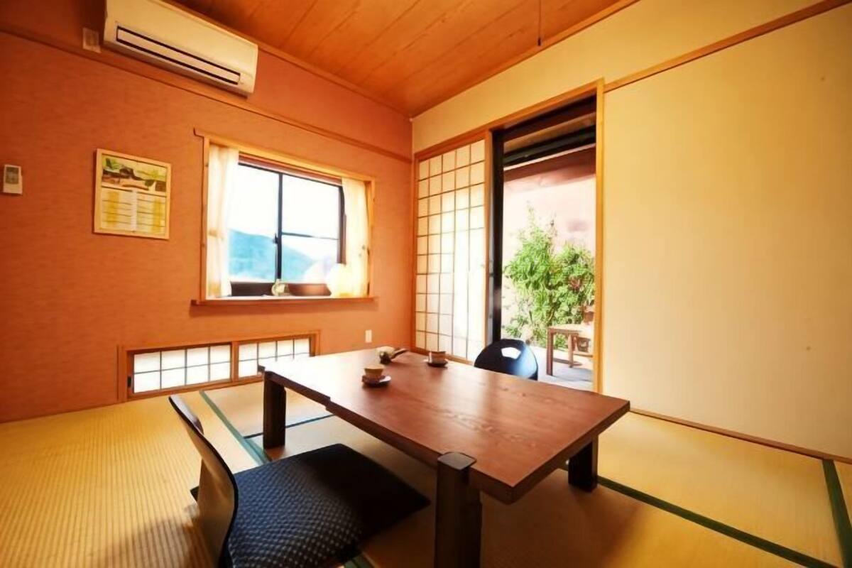 Um quarto japonês tradicional com piso de tatame, uma mesa baixa, uma janela com vista e um futum.