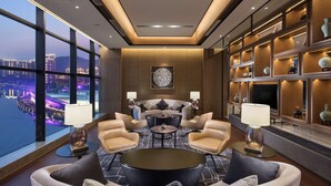 Um hall de hotel moderno com uma ampla área de estar, lareira e vista para a cidade.