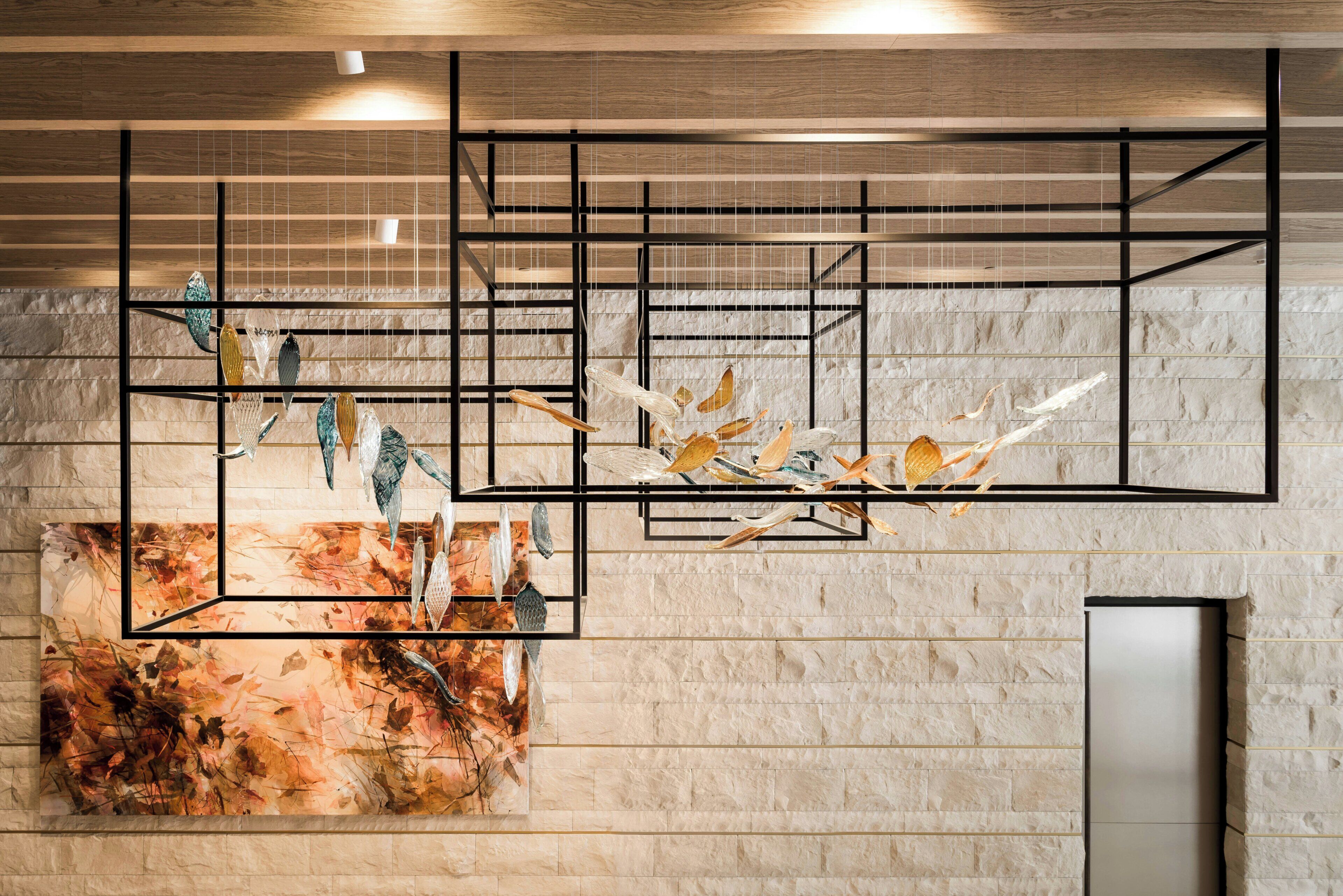 Um interior moderno com estrutura metálica geométrica, parede texturizada e uma grande pintura abstrata.
