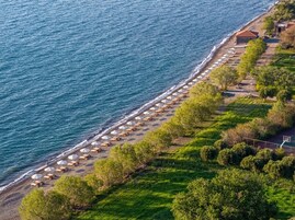 Na praia, areia preta, espreguiçadeiras, guarda-sóis 