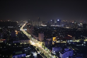 Vista aérea de uma paisagem urbana noturna, com edifícios, ruas e tráfego iluminados.