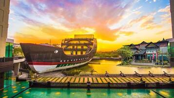 Um grande navio atracado em frente a um hotel à beira-mar, com vista para o pôr do sol.