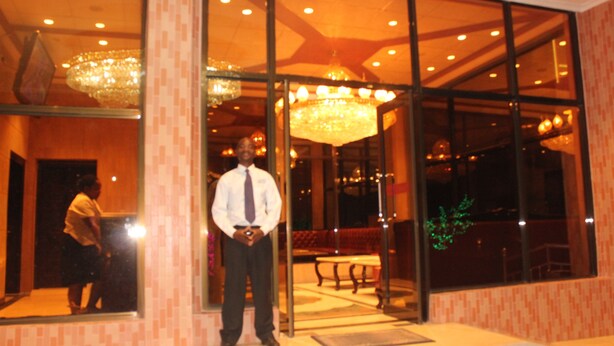 Um homem em frente a um edifício com grandes janelas de vidro e um candelabro.