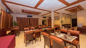 Uma área de refeições de hotel com várias mesas e cabines, dispostas num espaço amplo.