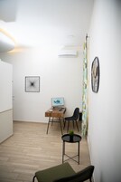 Um espaço de estar compacto com uma escrivaninha de madeira, um computador, uma pequena mesa com uma planta e uma cadeira verde.