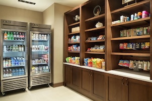 Uma estação de bebidas com serviço próprio, com dois refrigeradores e diversos snacks e artigos de higiene pessoal.