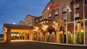 Um hotel com estilo arquitetônico tradicional, apresentando entradas em arco e fachada bem iluminada.