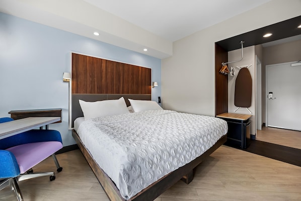 Quarto de hotel moderno com cama, escrivaninha, cadeira e guarda-roupa.
