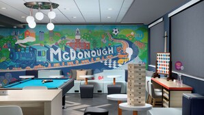 Espaço de recreação infantil vibrante, com mesa de bilhar, assentos e um mural colorido.
