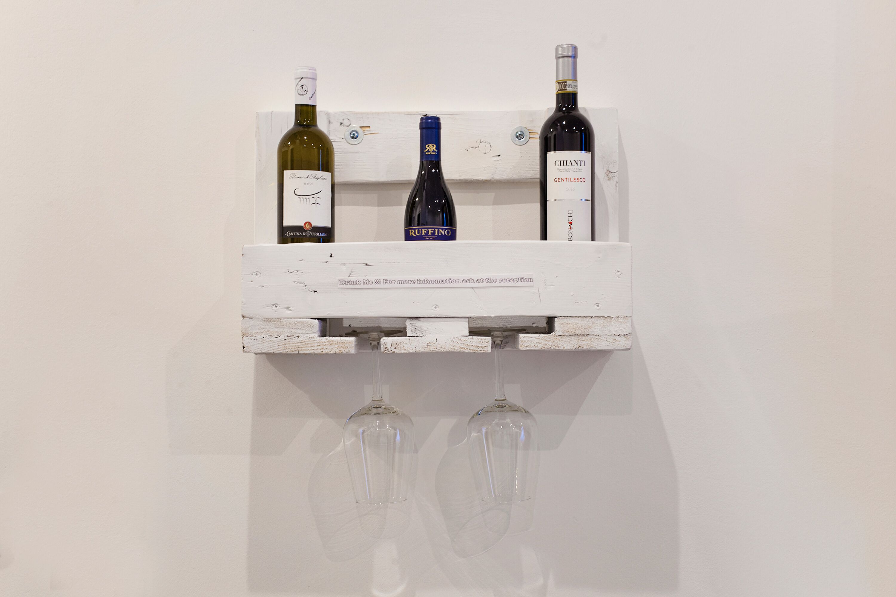Uma adega com três garrafas e dois copos de vinho.