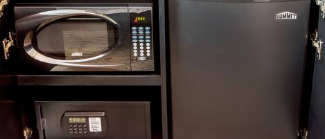 Um micro-ondas e uma geladeira pretos em um armário de cozinha.