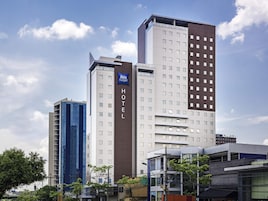 Um hotel moderno com uma placa de destaque 'ibis budget', vários andares e fachadas de vidro e concreto.