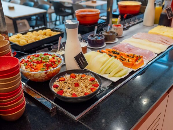 Buffet com diversas opções de comida, incluindo frutas, legumes e uma variedade de pratos.