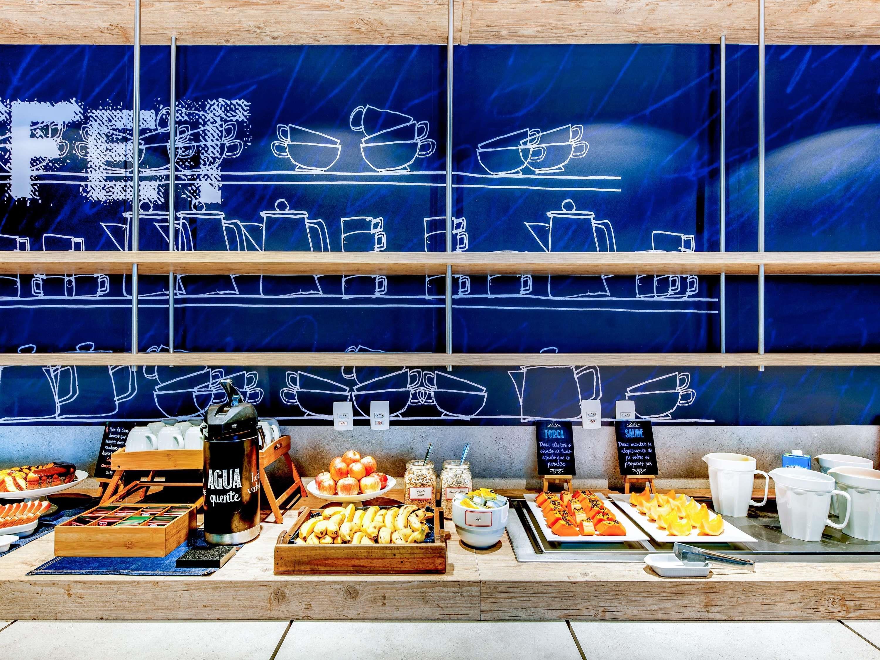 Disposição de buffet com diversos alimentos e uma lousa exibindo desenhos de xícaras de café.