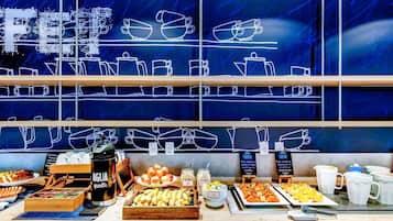 Disposição de buffet com diversos alimentos e uma lousa exibindo desenhos de xícaras de café.