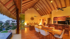 Uma sala de estar ampla com uma mesa de jantar, cadeiras, um sofá e um ventilador de teto.