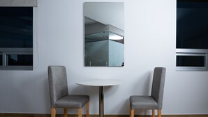 Quarto moderno com uma mesa redonda e duas cadeiras cinzas estofadas.