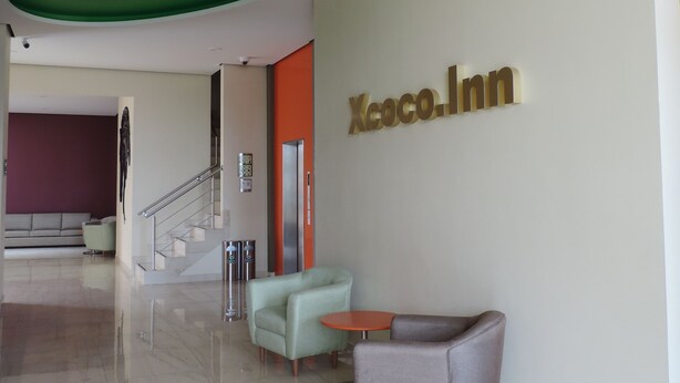 Um hall de hotel moderno com teto verde, balcão de recepção e escadaria.