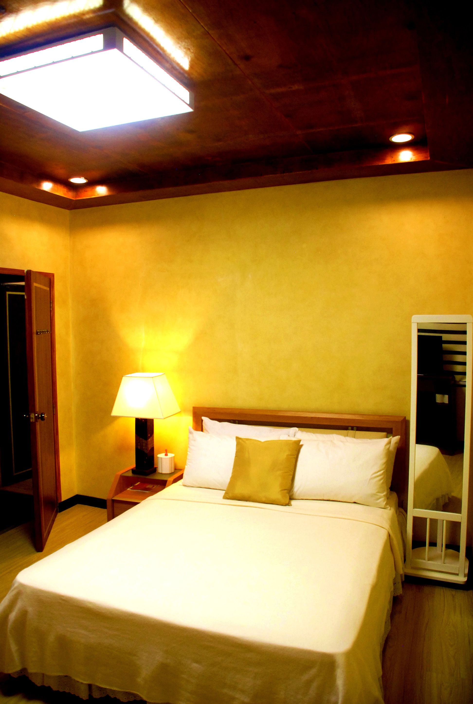 Quarto de hotel com uma cama grande, uma luminária de cabeceira e um guarda-roupa.