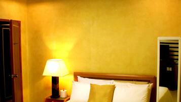 Quarto de hotel com uma cama grande, uma luminária de cabeceira e um guarda-roupa.